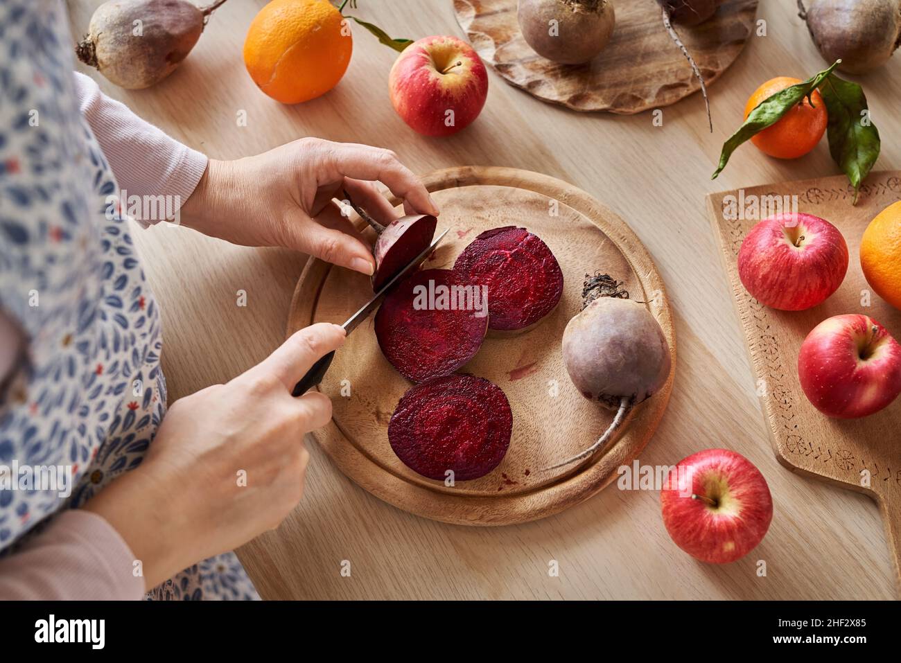 Woman cutting red beet root - preparation for juicing fresh fruits and ...