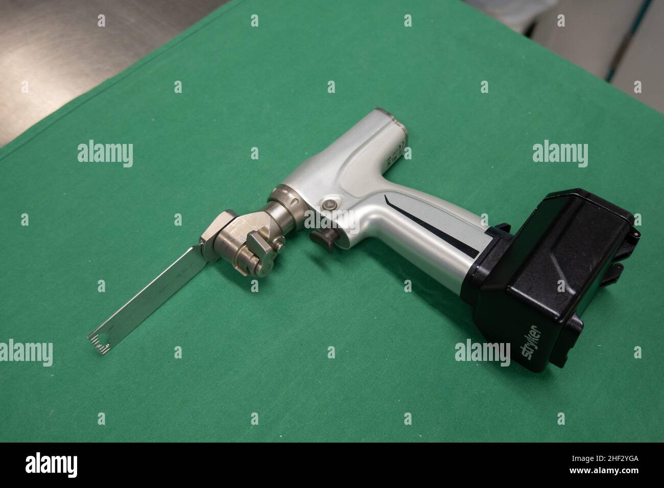 battery powered surgical oscillating saw with saw blade lies on a green ...