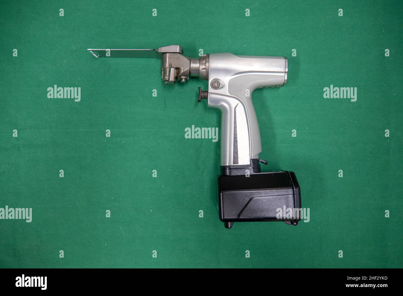 battery powered surgical oscillating saw with saw blade lies on a green ...