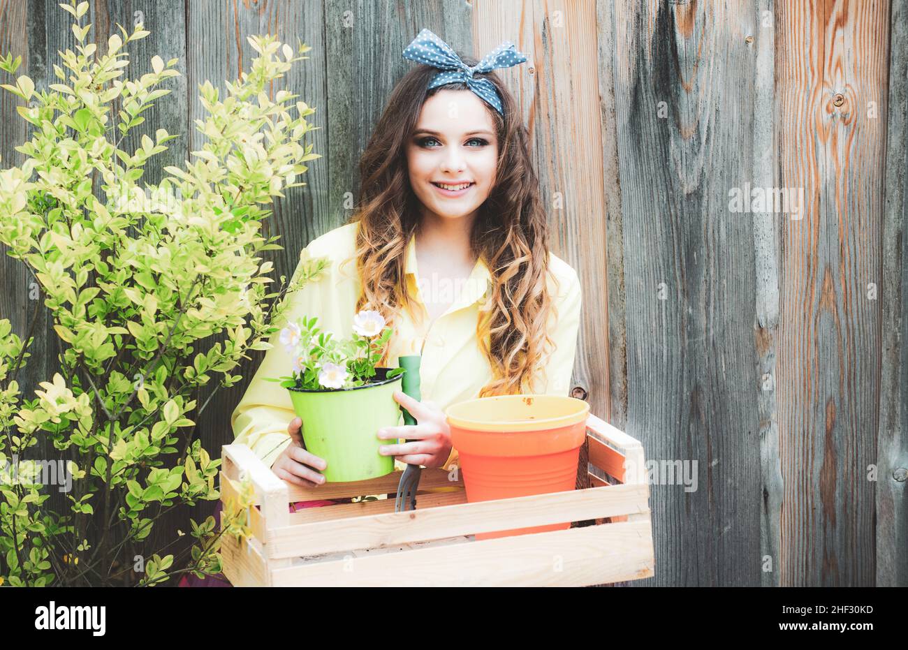 Pretty smiling girl holding garden tools at wooden background. Planting ...