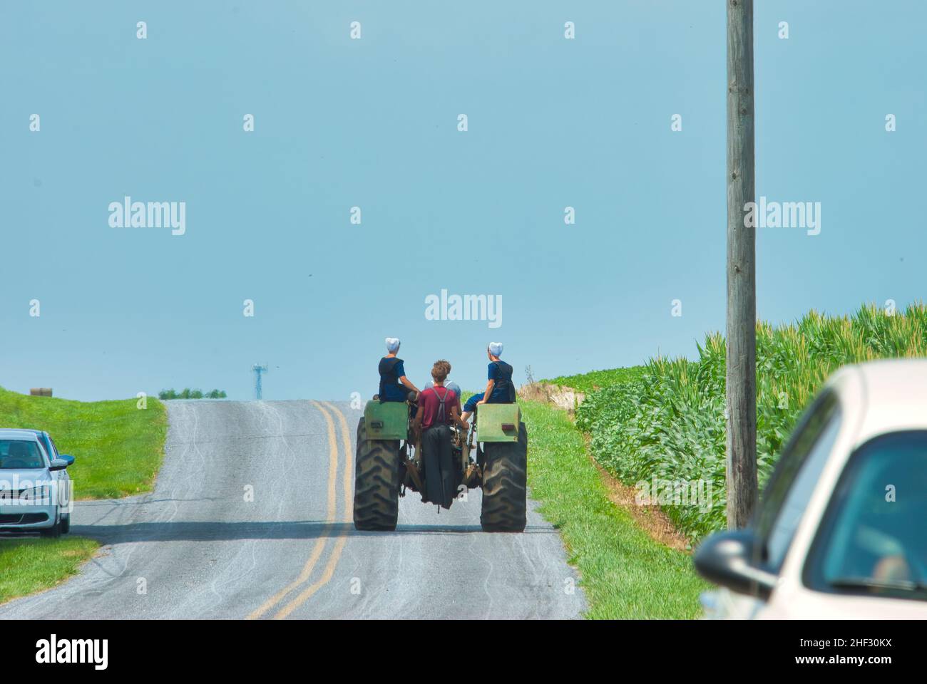 Amish Boy and Girl Teenagers Riding on a Old Tractor Thru Farmlands on ...
