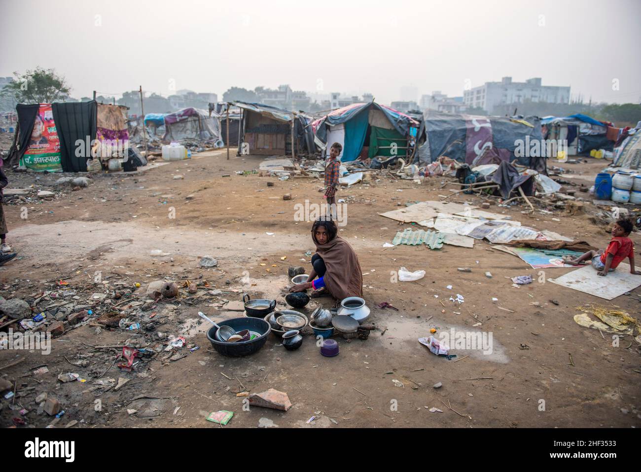 A slum dweller woman seen washing utensils in an unhygienic space in ...