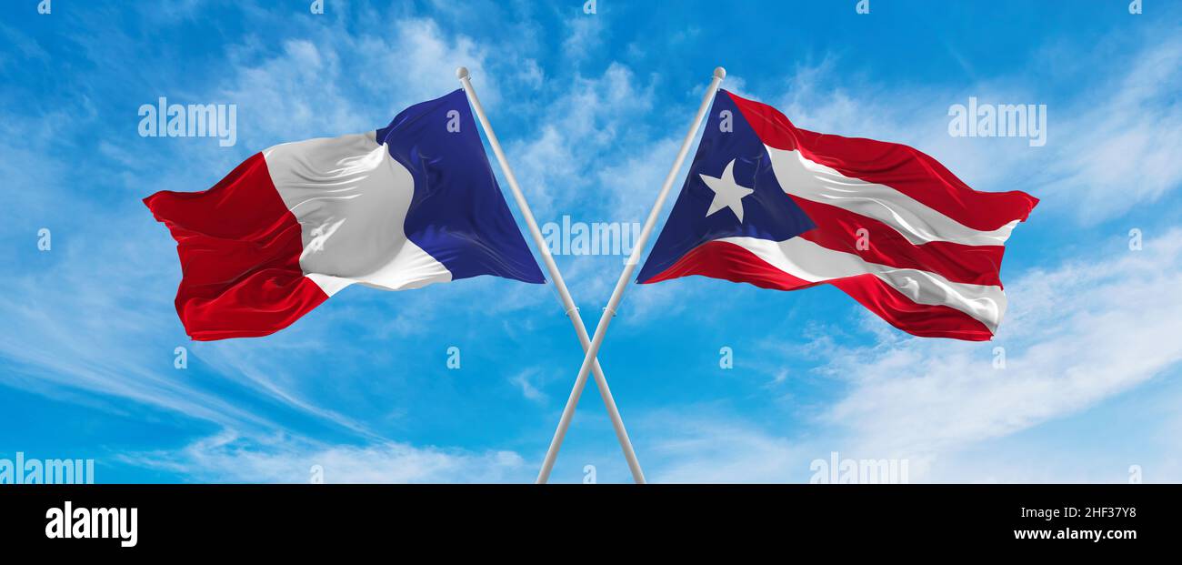 crossed national flags of France and Puerto Rico flag waving in the wind at cloudy sky ...