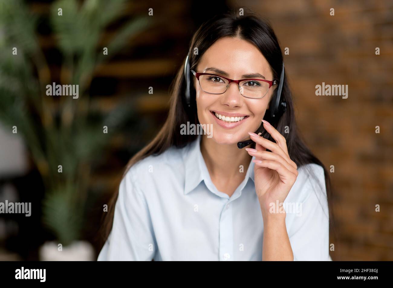 Pretty, positive caucasian brunette woman, wearing headset and glasses ...