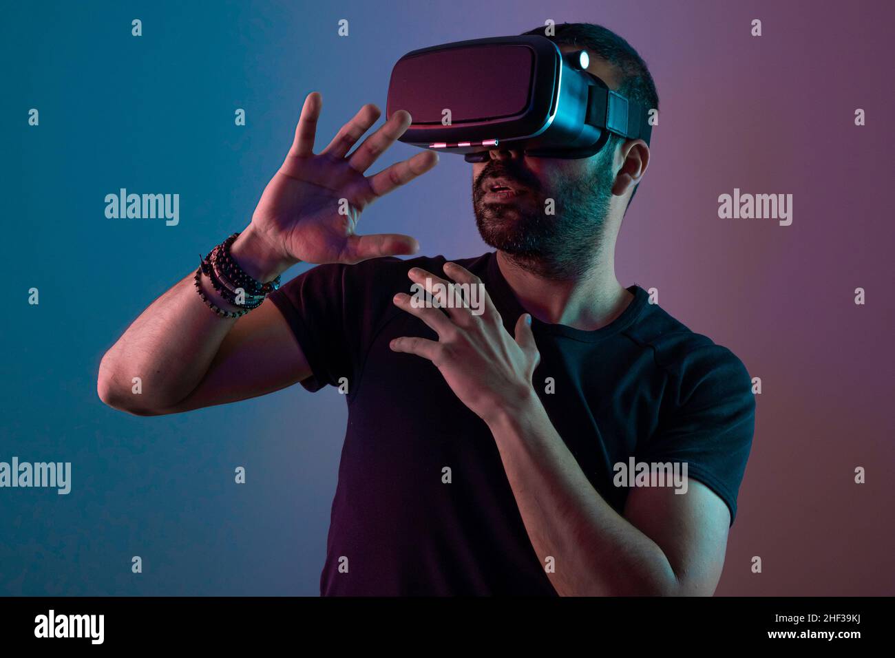 Young man in VR glasses excited interact with virtual reality in color ...