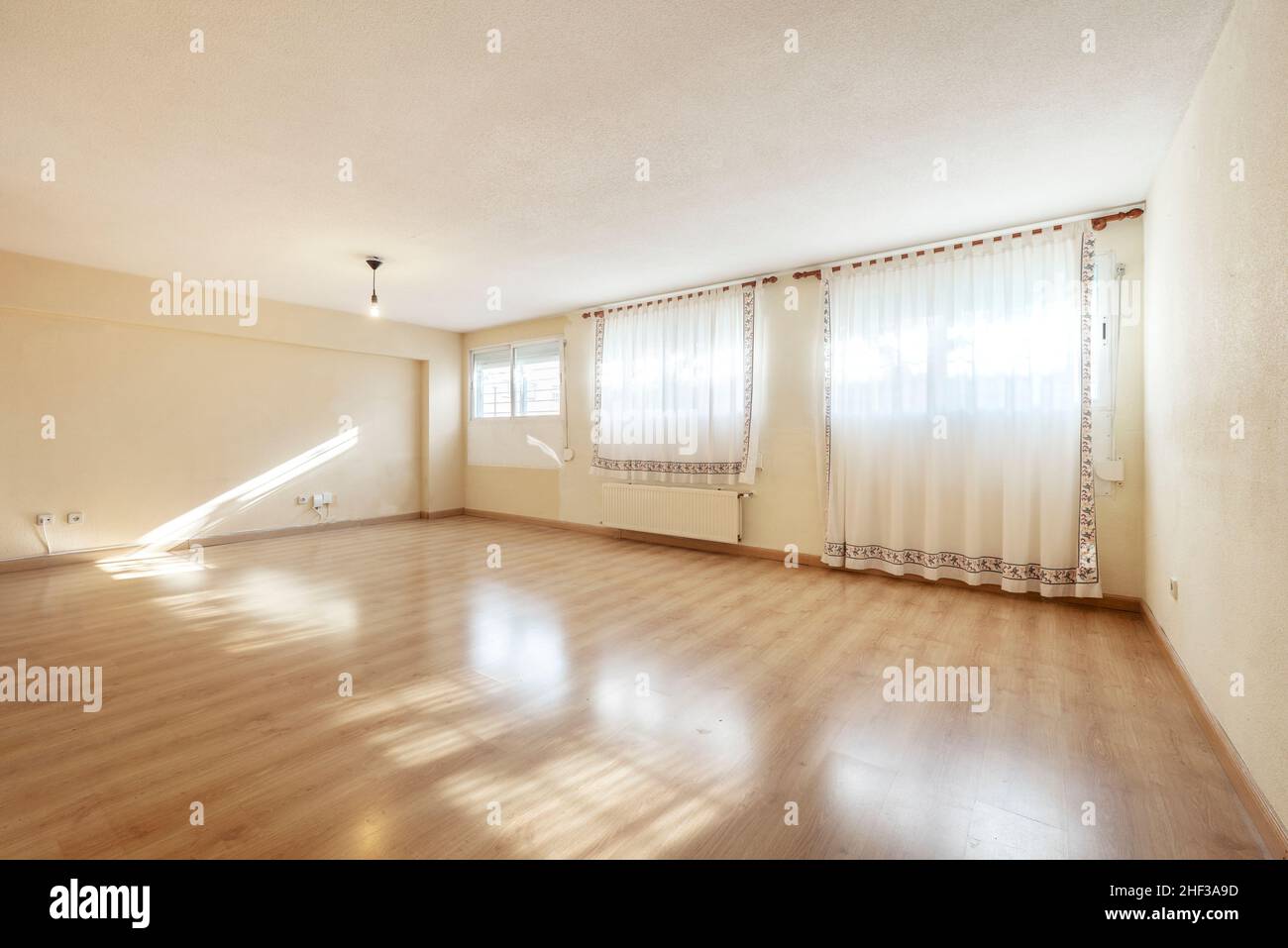 Large empty living room with curtains on the windows and wooden ...