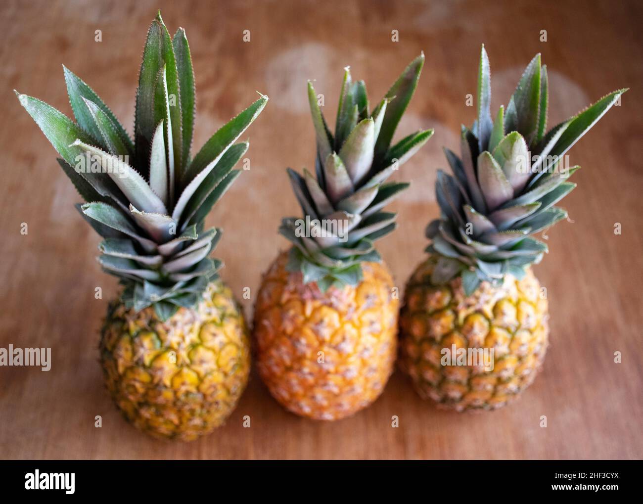 Three tropical pineapples with wood background in top view Stock Photo ...