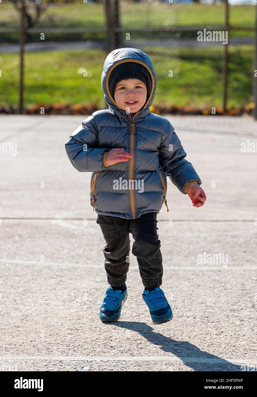 Two year old boy running on city park playground; Corinthian Gardens ...