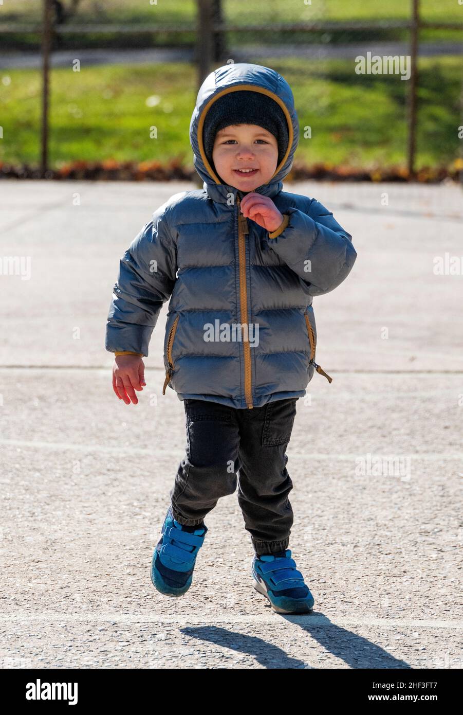 Two year old boy running on city park playground; Corinthian Gardens ...