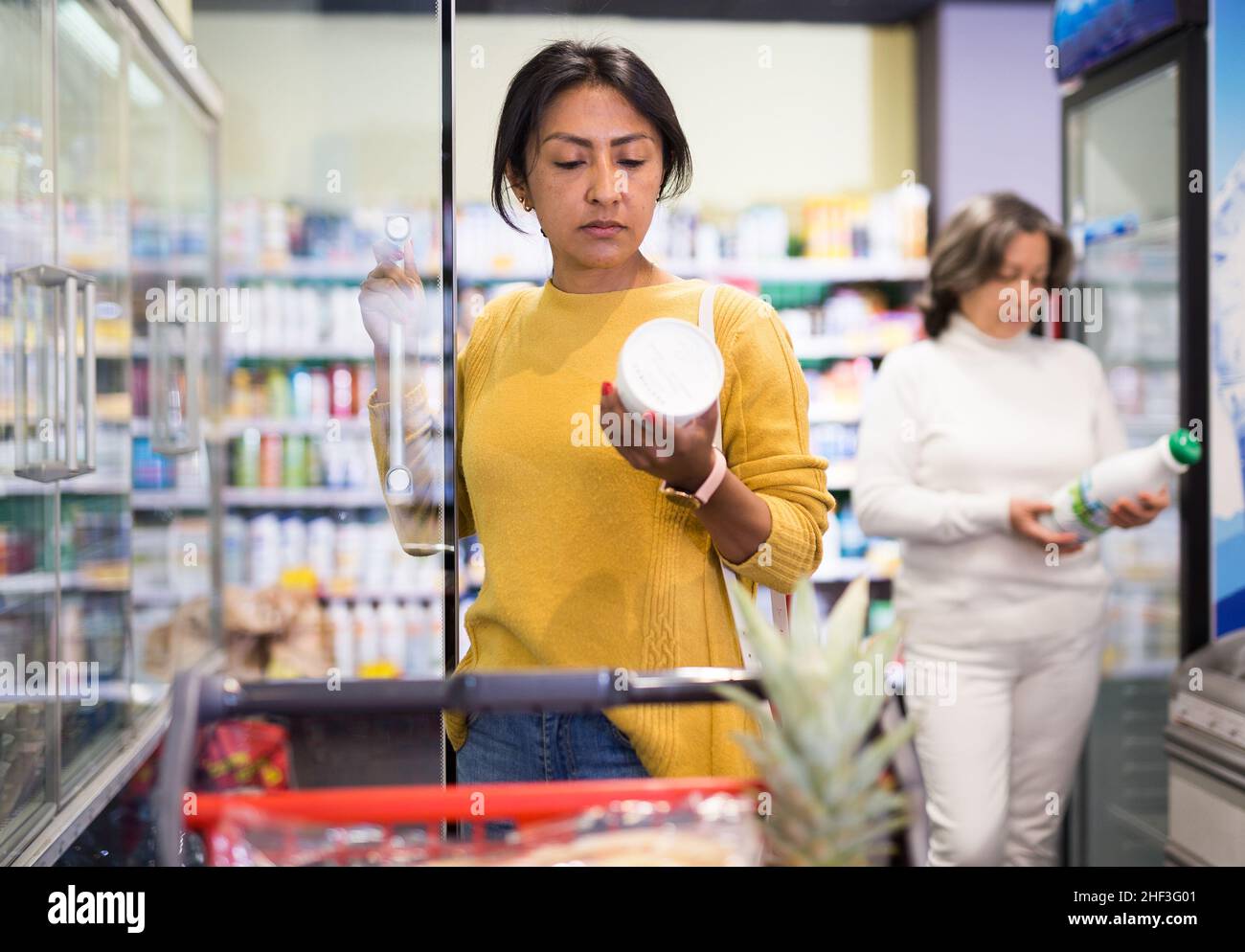 Latin american woman choosing dairy products in grocery shop Stock ...
