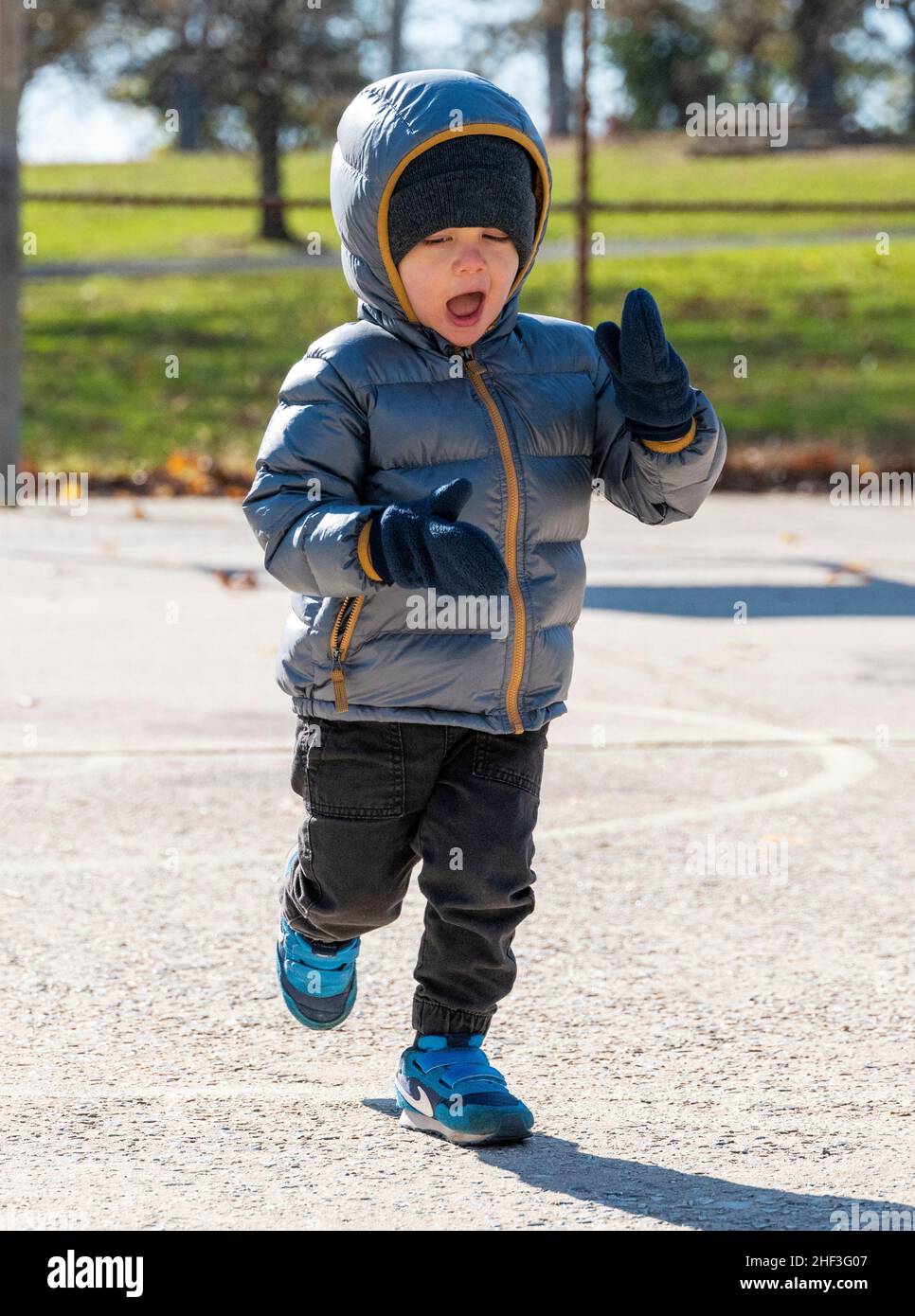 Two year old boy running on city park playground; Corinthian Gardens ...