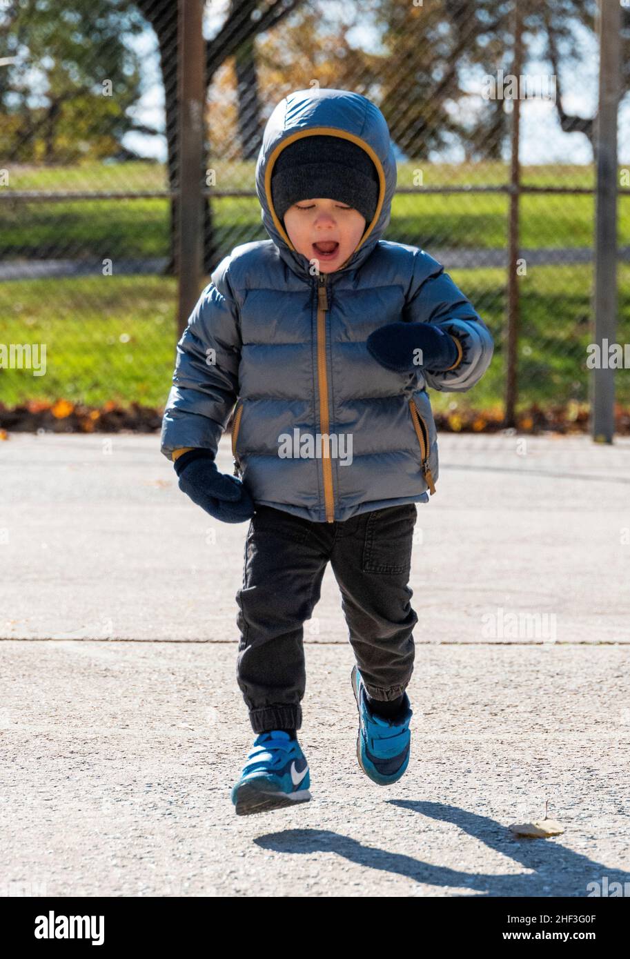Two year old boy running on city park playground; Corinthian Gardens ...