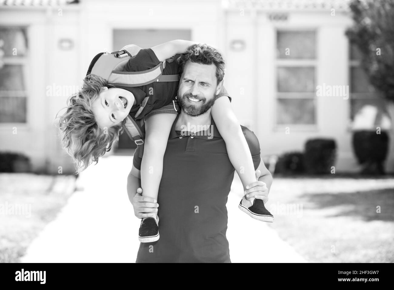 School boy going to school with father. Man giving son piggyback ride ...