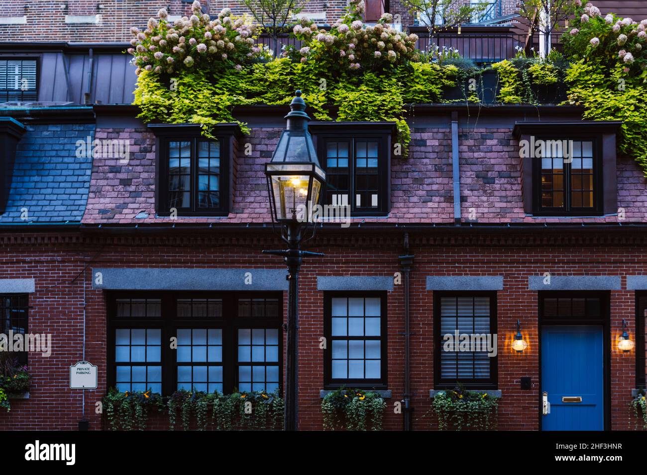 Red brick wall apartment buildings with flowers at window and lanterns ...