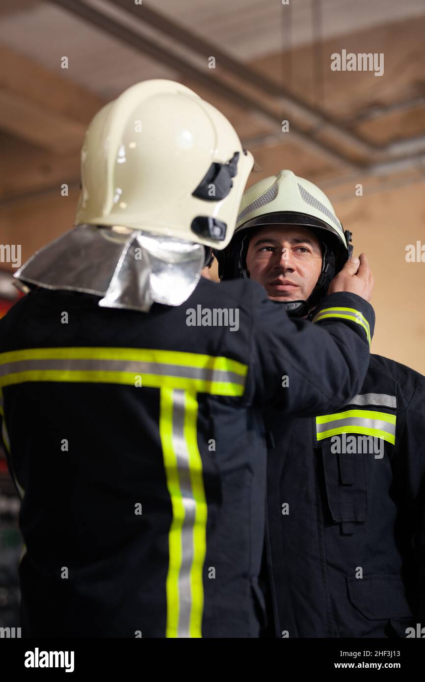 Professional firefighters wearing uniforms. Fireman putting on ...