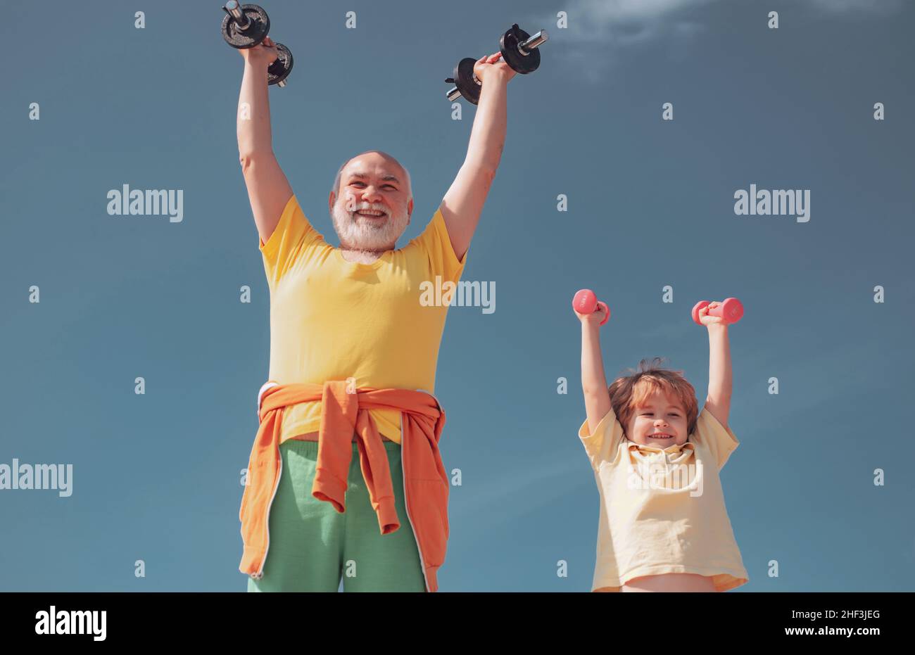 Grandfather helping kid exercising with dumbbells. Senior man and child ...