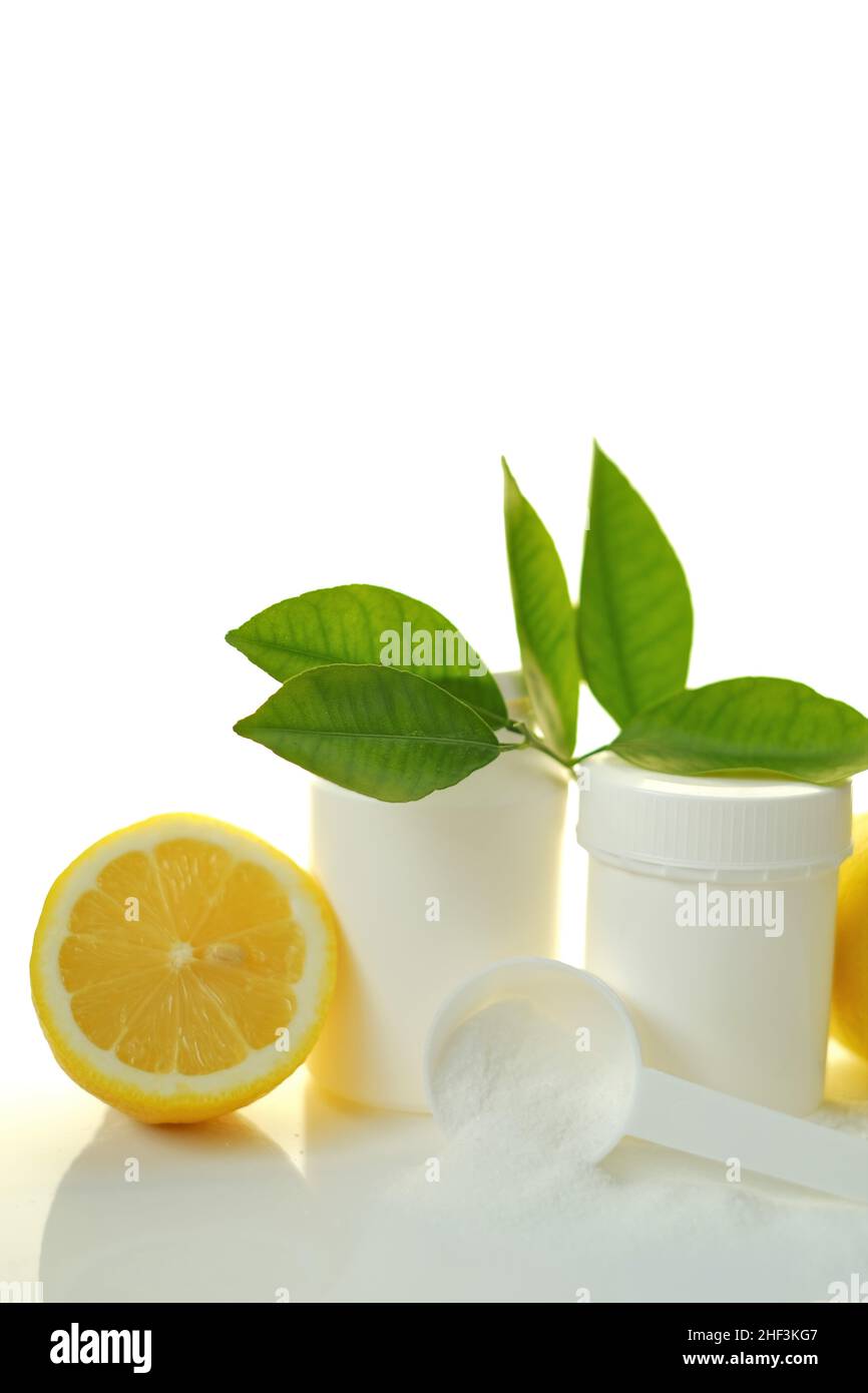 Vitamin C powder, white spoon, white jar and lemon in a cut with green ...