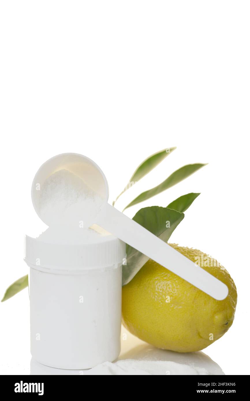 Vitamin C powder, white measuring spoon, white jar and lemon with green ...