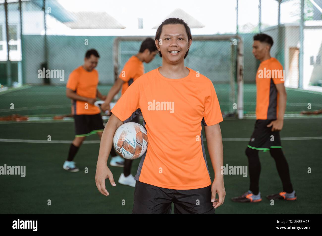 male futsal player smiling while carrying the ball Stock Photo - Alamy