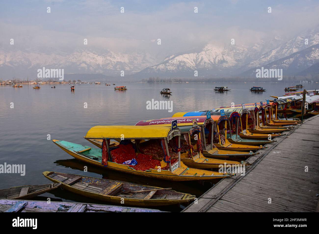 Boats are seen moored to the bank of Dal Lake during a cold winter day ...