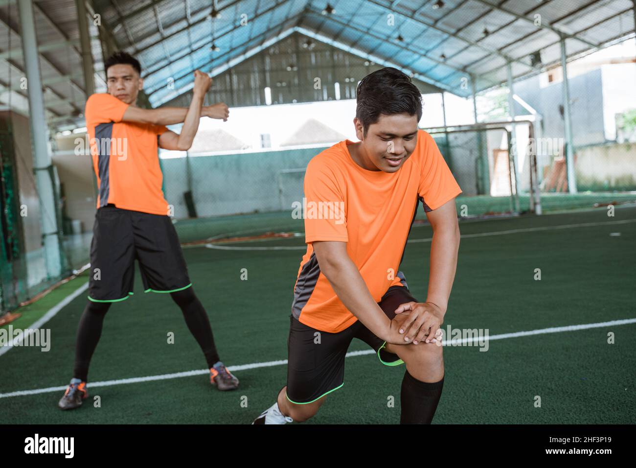 two futsal players stretching their legs and arms Stock Photo - Alamy