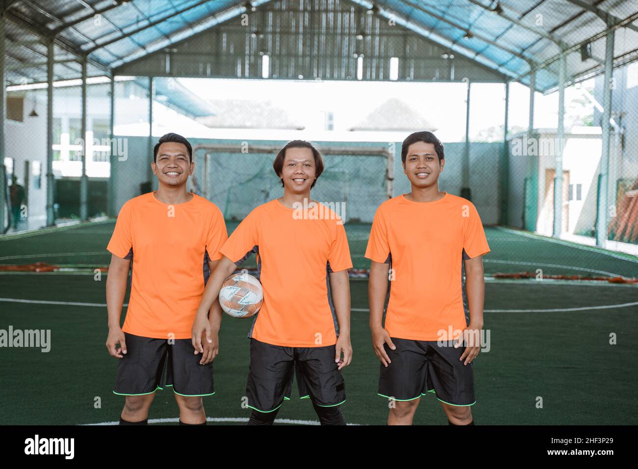 Three futsal players standing carrying the ball Stock Photo - Alamy