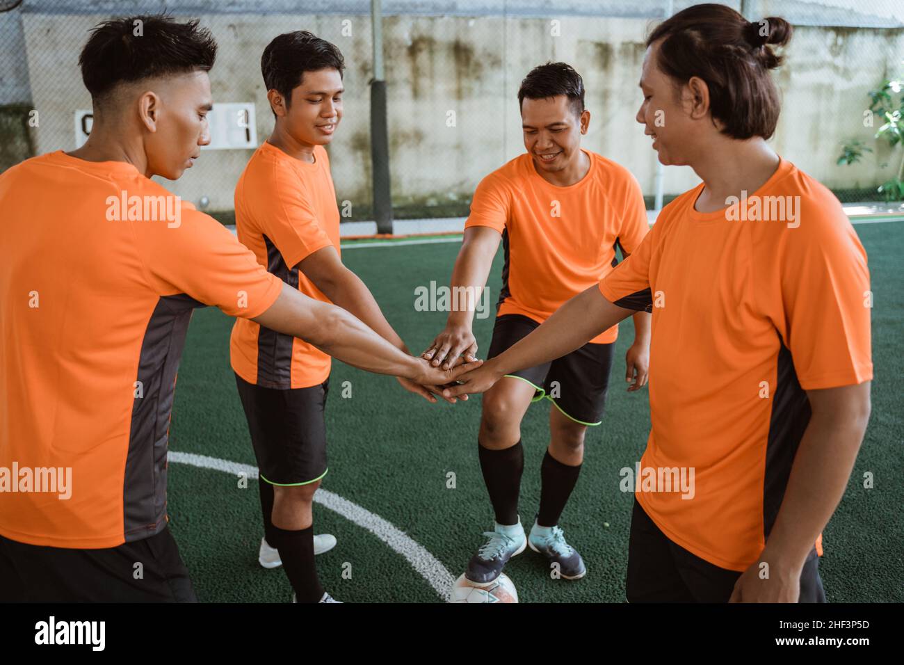 Male players in orange uniforms gather in a circle Stock Photo - Alamy