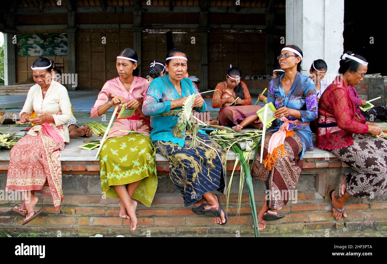 Colorfully traditionally dressed women makling Canang Sari Hindu ...