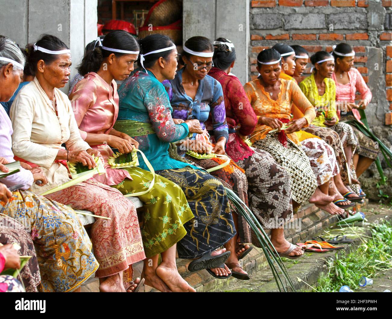 Colorfully traditionally dressed women makling Canang Sari Hindu ...