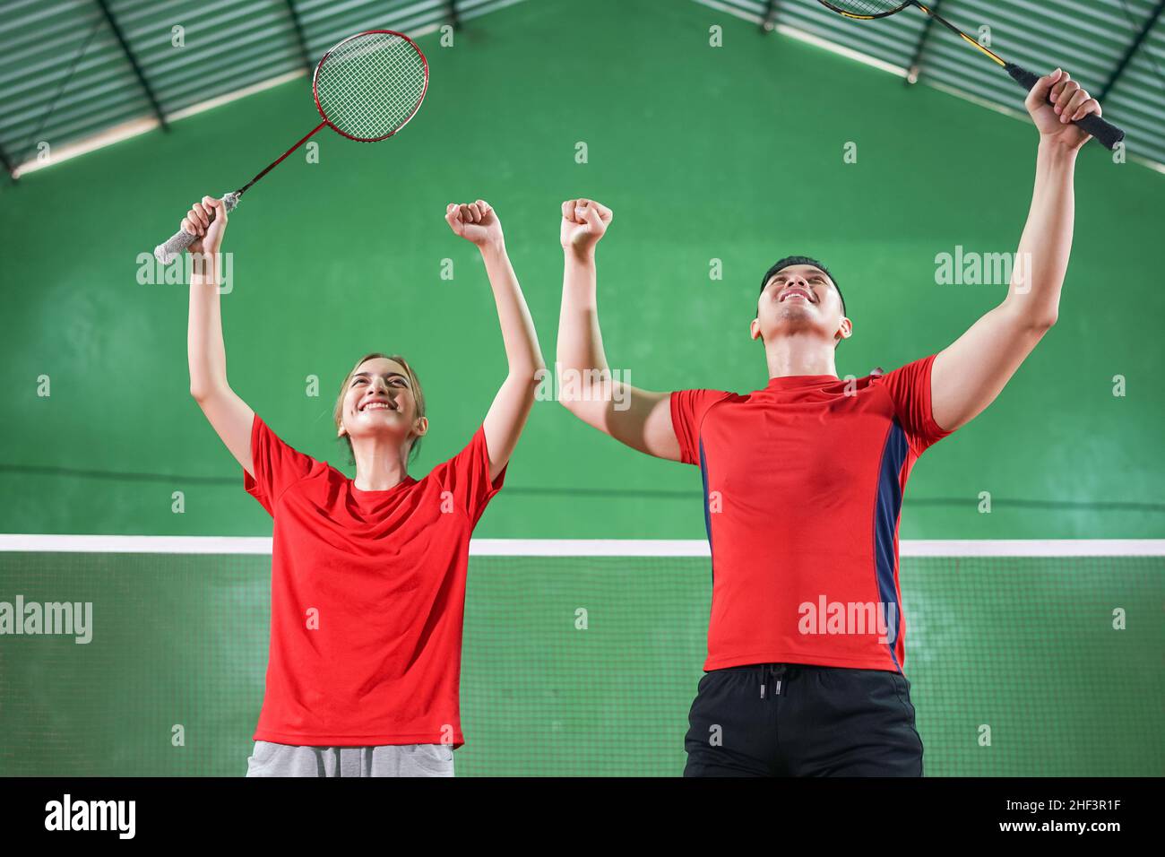excited badminton players raise their hands on the court Stock Photo ...