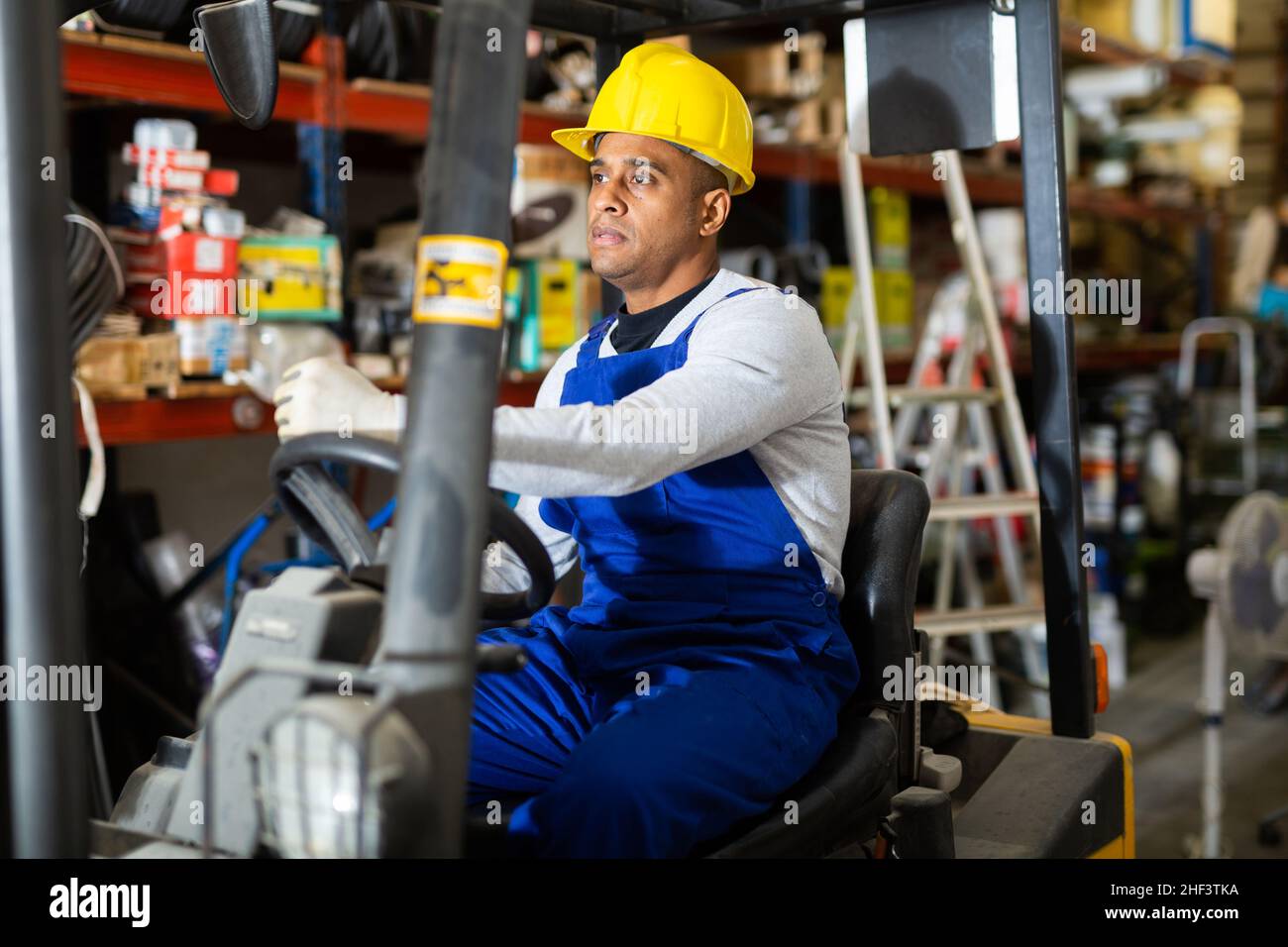 Hispanic worker of building materials warehouse driving forklift truck ...