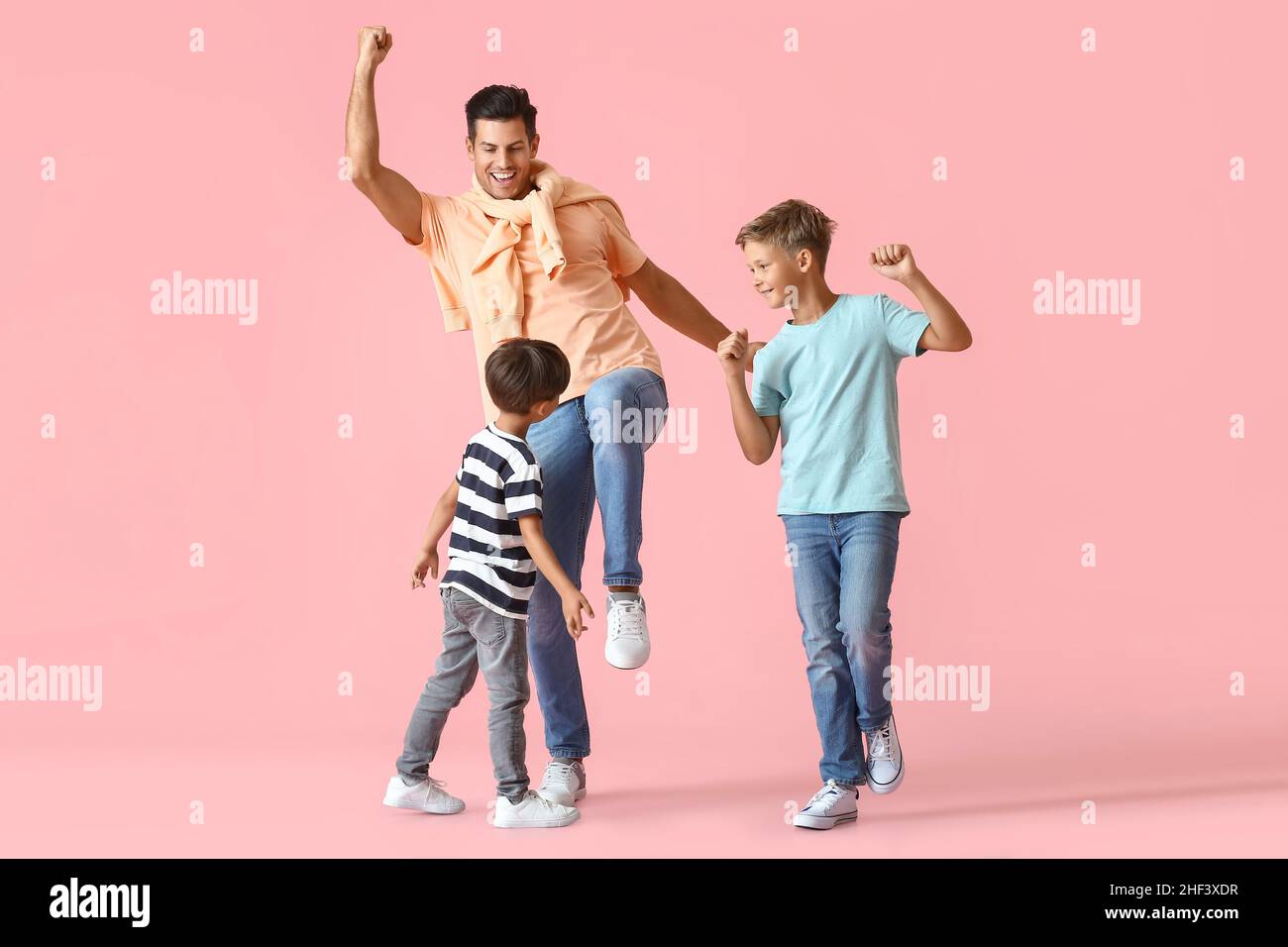 Happy dancing man and his sons on color background Stock Photo - Alamy
