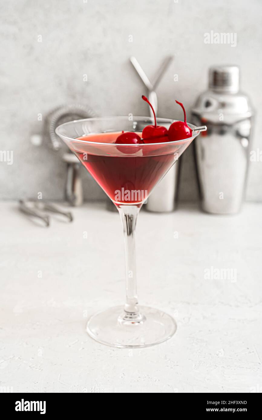 Glass of tasty Manhattan cocktail with cherries on light background ...