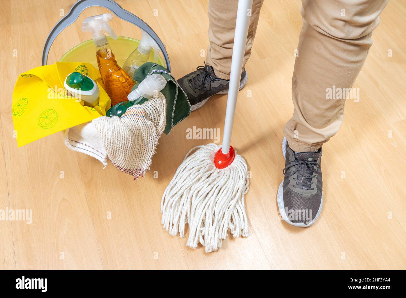 A Bucket of cleaning supplies next to the legs of a man holding a rope ...