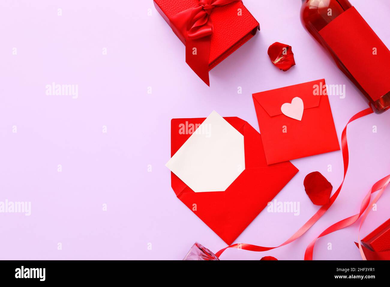 Composition with cards, bottle of wine and rose petals on color background. Valentine's Day ...