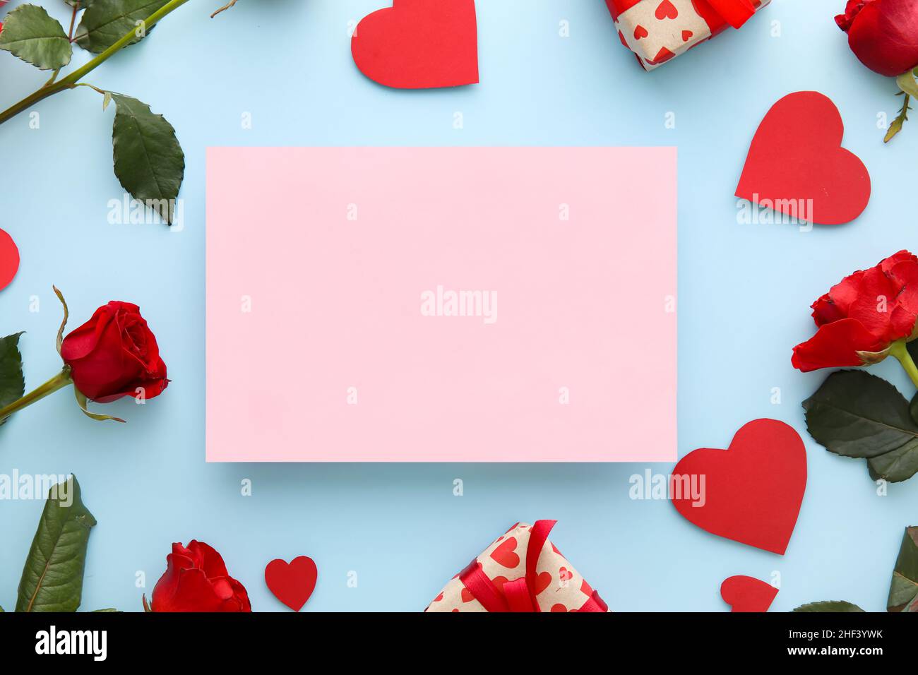 Composition with blank card, rose flowers and paper hearts on blue ...