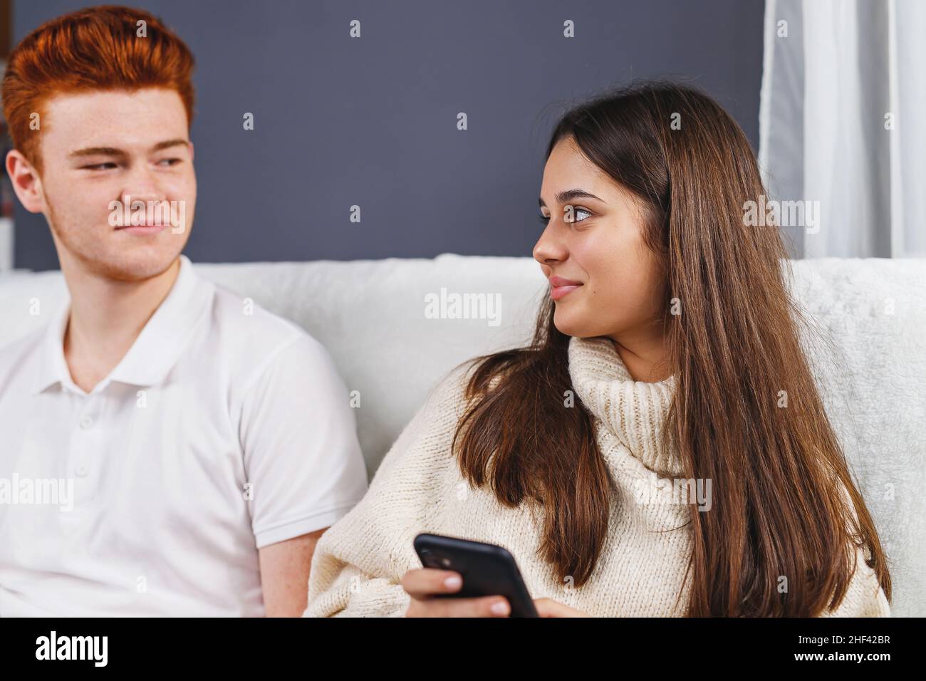 Close up photo of loving young couple looking at each other flirting ...