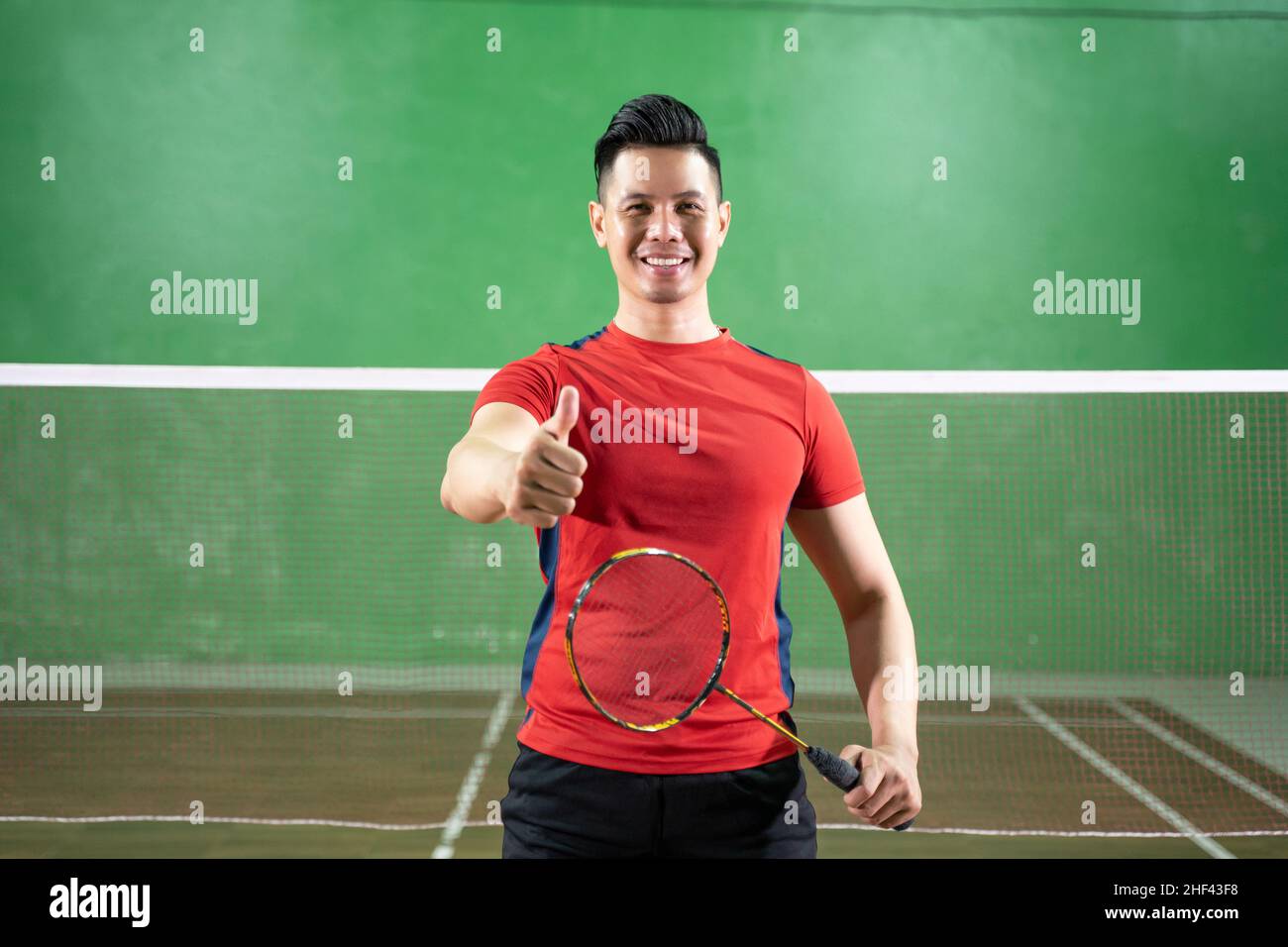 Smiling male badminton player holding racket with thumbs up Stock Photo ...
