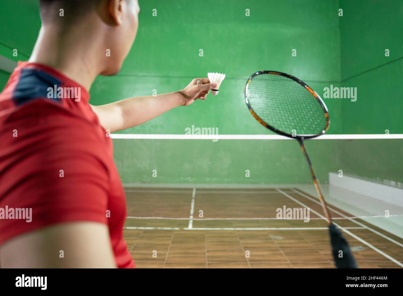 Male badminton player holding shuttlecock and racket in service ...