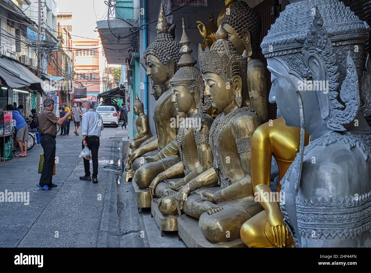 A row of different Buddha statues is placed outside a shop for Buddhist ...
