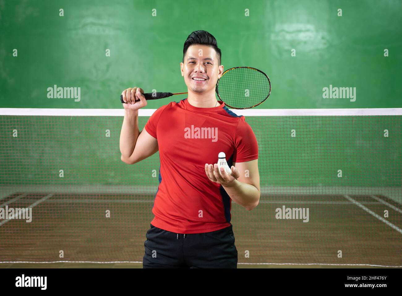 Handsome badminton player standing holding racket and shuttlecock Stock ...