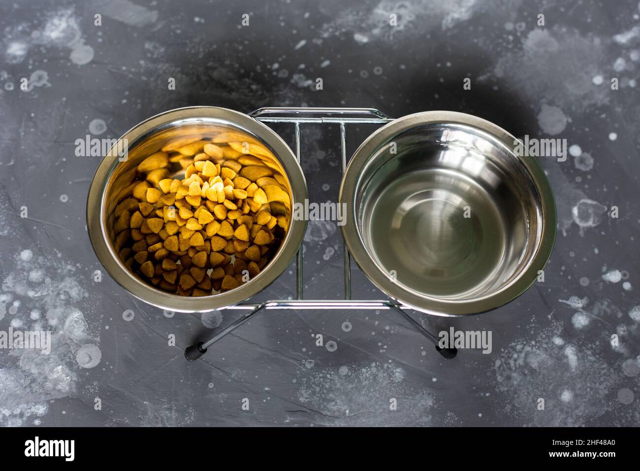 Hand pouring dry food into a steel bowl for cattle. Feeding your pet ...