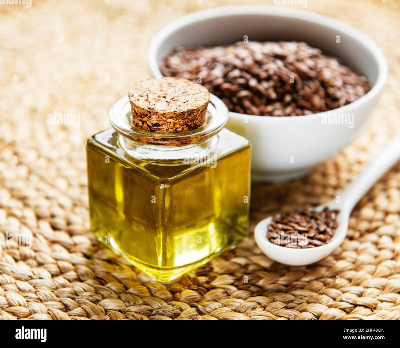 Flax seeds or linseeds in spoon and bowl with glass of linseed oil on ...