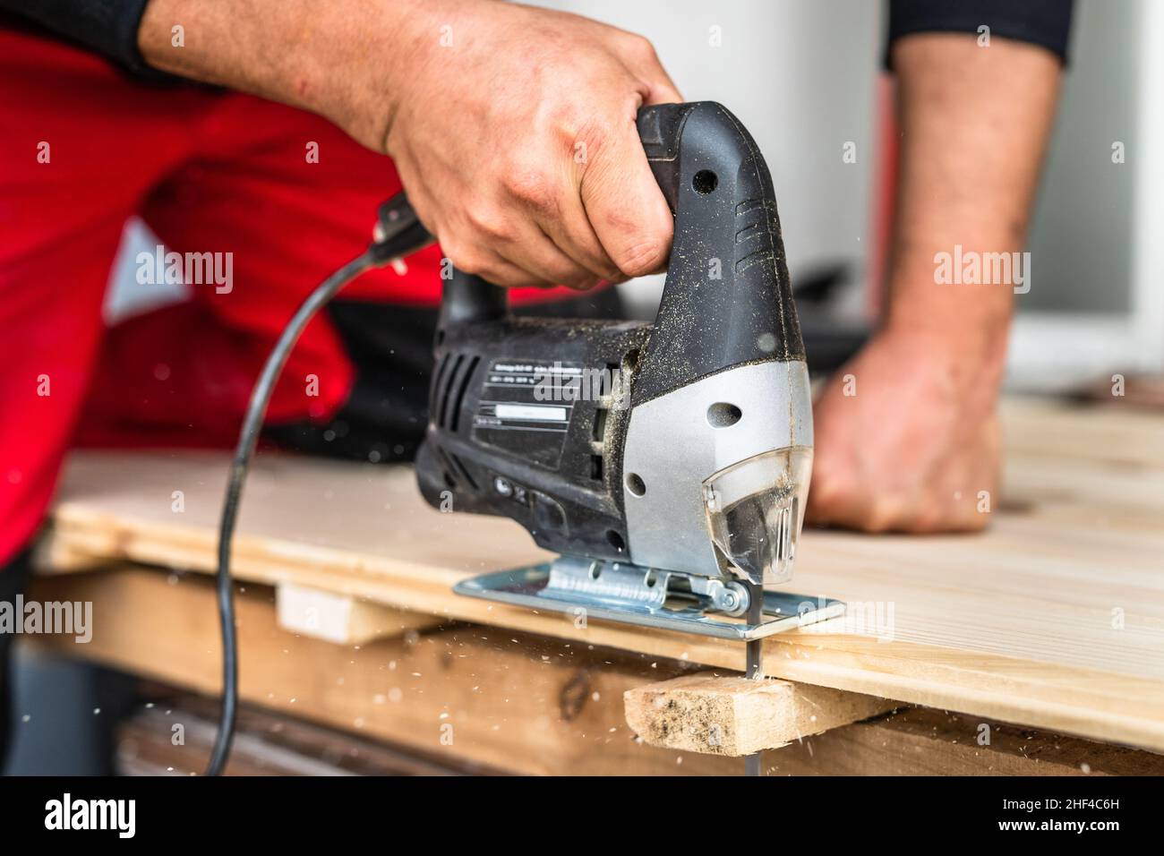 Close up on hand of unknown carpenter working with an electric jigsaw ...