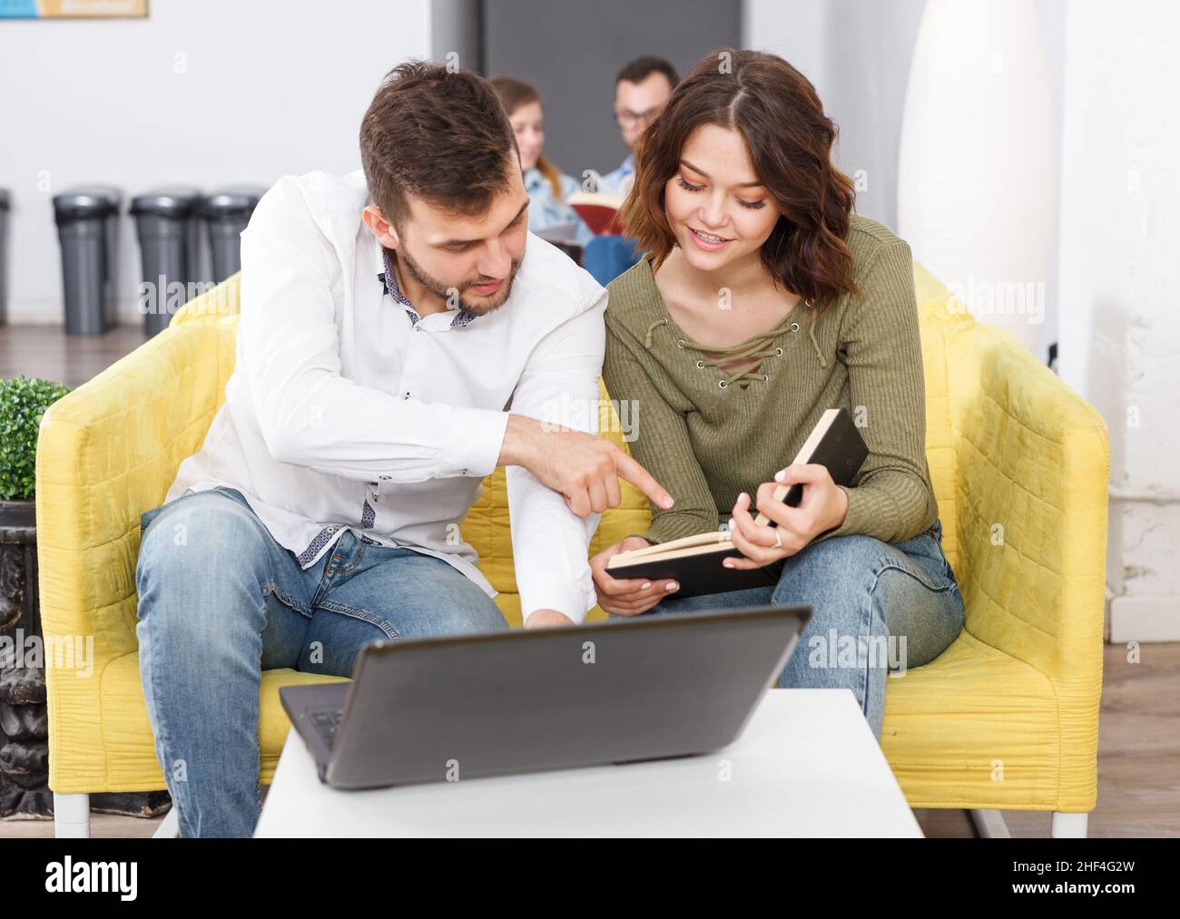 Young people with laptop and book Stock Photo - Alamy
