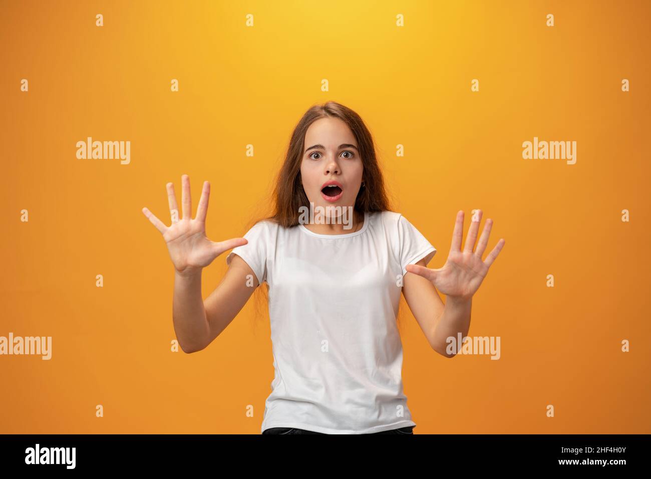 Scared young teen girl showing stop gesture against yellow background ...