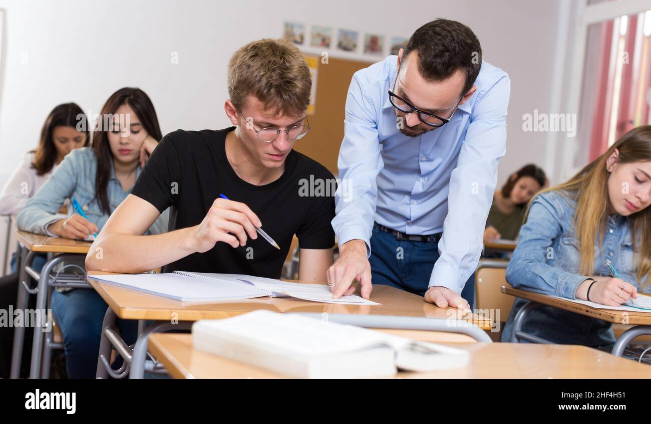 Young boy is writing test and teacher is explaining about questions ...