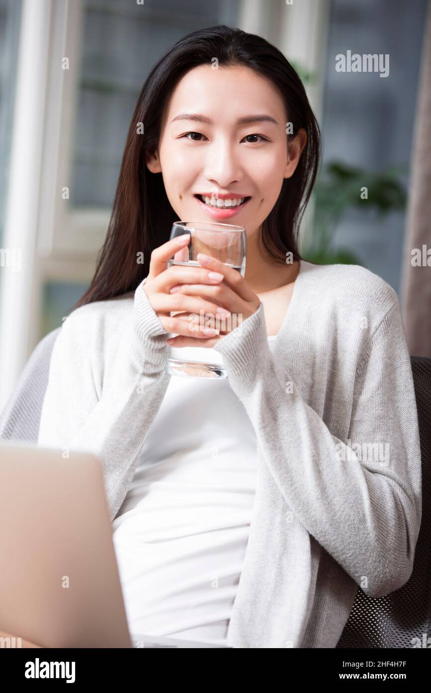 Happy young woman drinking water at home Stock Photo - Alamy