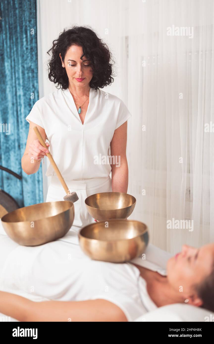 Beautiful female therapist practicing sound healing therapy over pretty ...