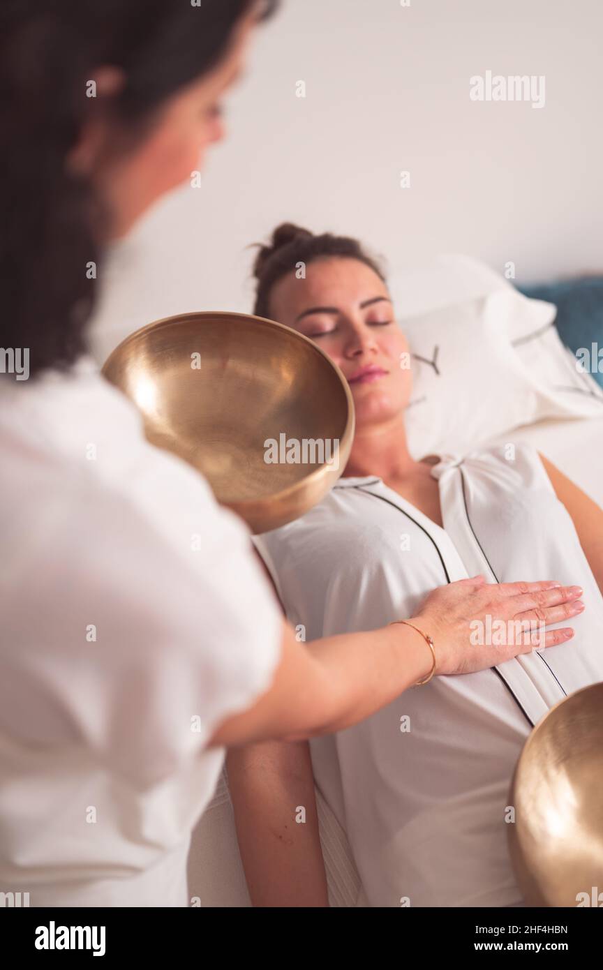Female therapist with singing bowl practicing sound healing therapy on ...